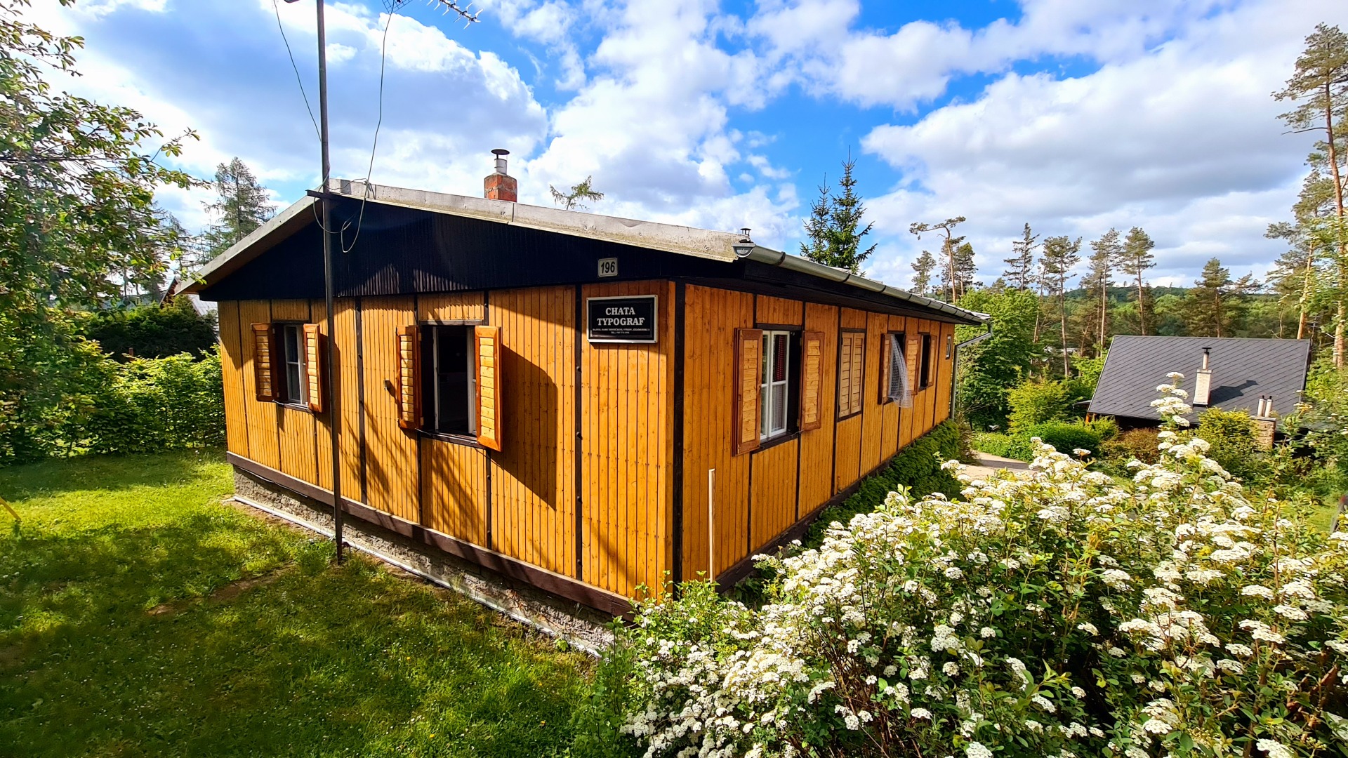 Chata Jedovnice - dřevem obložená chata se zastřešenou terasou u lesa v ...